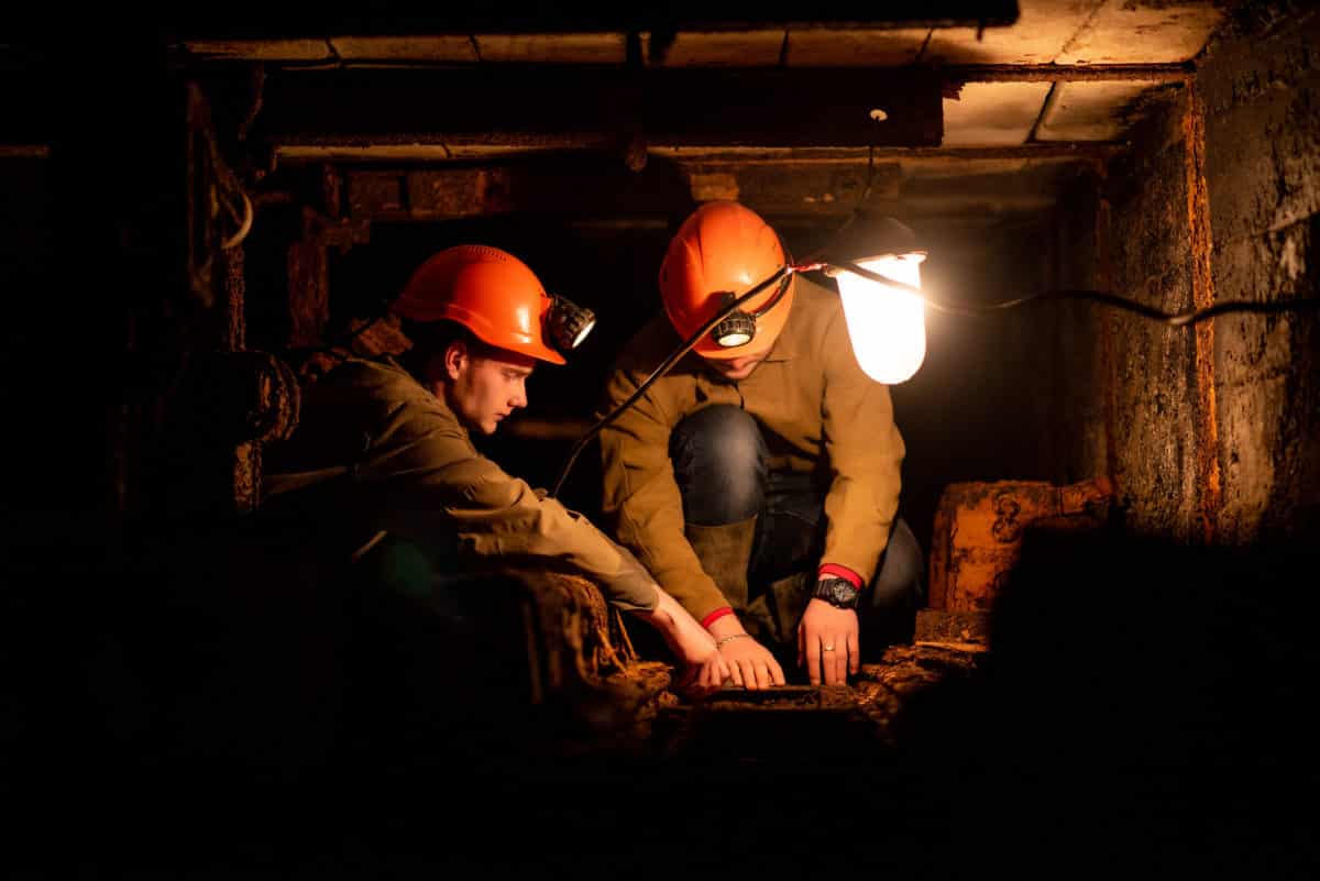 Two young guys in a working uniform and protective helmets, sitting in ...